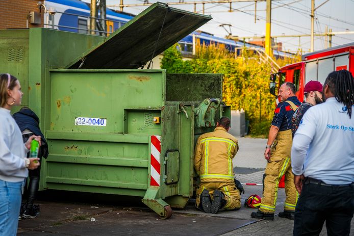 Man klimt in container met afvalpers bij station Eindhoven, hulpdiensten rukken massaal uit ...