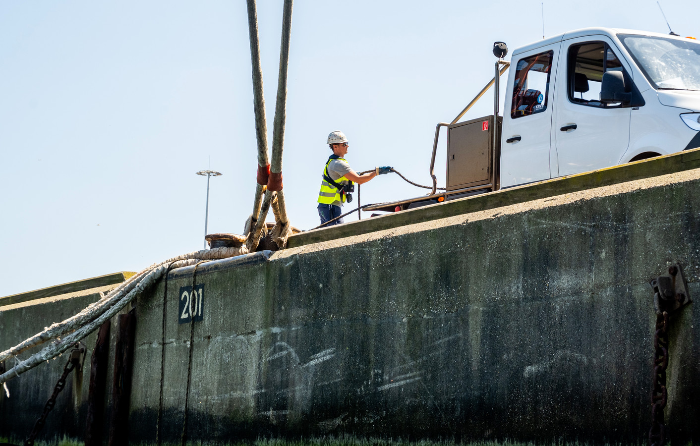 Met hun kleine bootjes leggen deze mannen immense schepen aan de kade ...