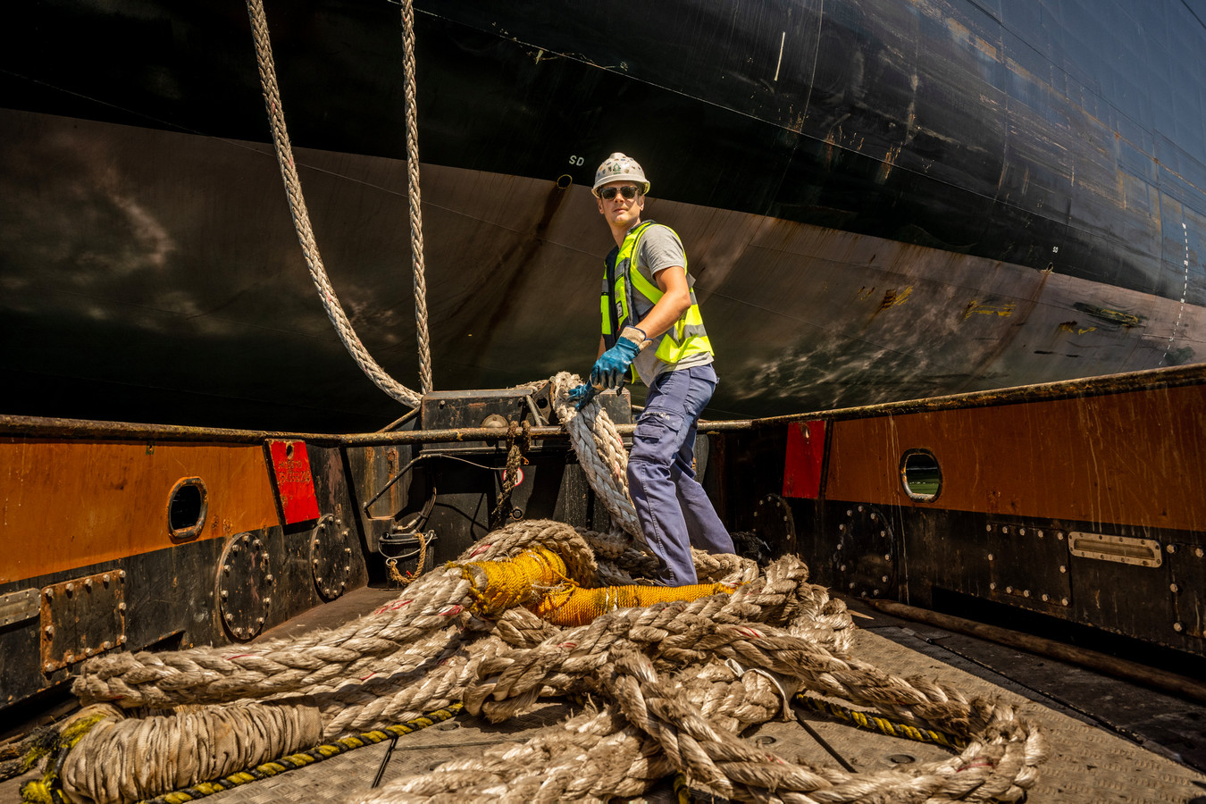 Met hun kleine bootjes leggen deze mannen immense schepen aan de kade ...
