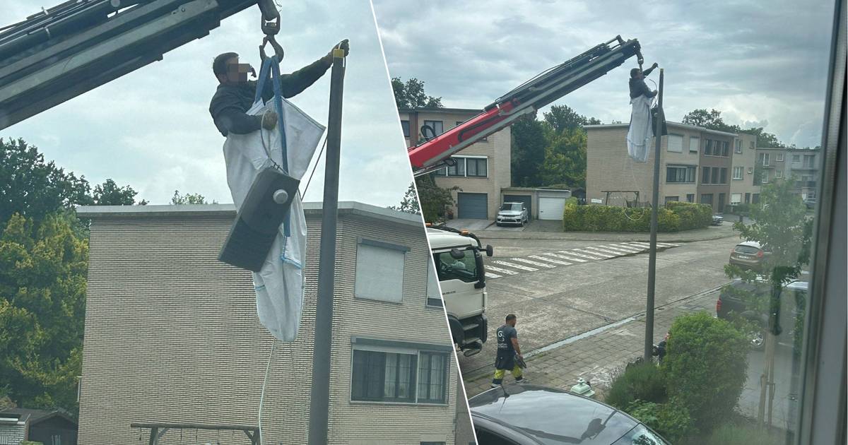 Fluvius-installateur herstelt verlichtingspaal al bengelend in een zak ...