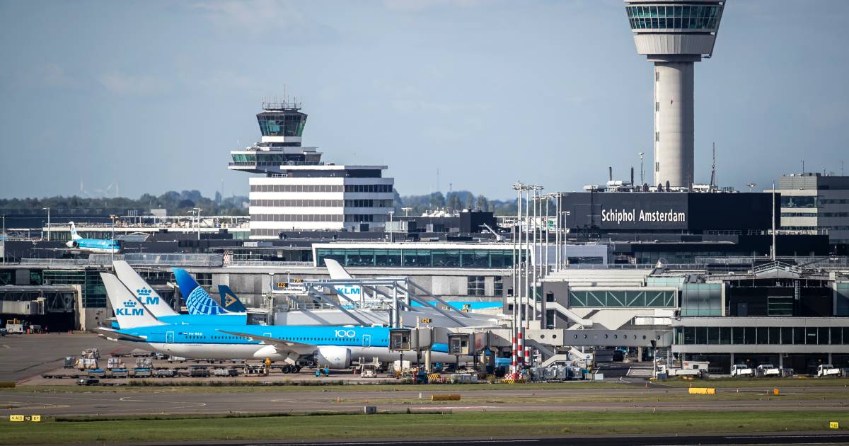 Man klimt met schaar in hand over balie wisselkantoor op Schiphol ...
