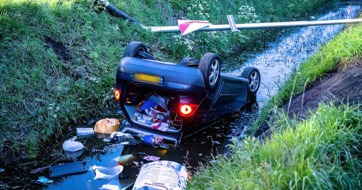Auto mist de bocht, ramt lantarenpaal en belandt ondersteboven in de ...