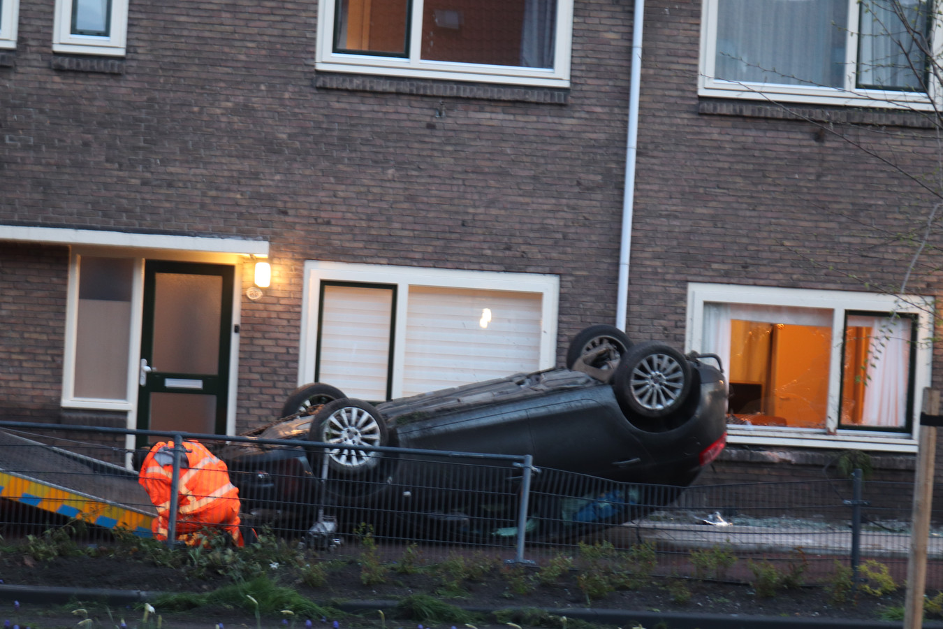 Auto vliegt over de kop en komt ondersteboven tot stilstand tegen huis ...